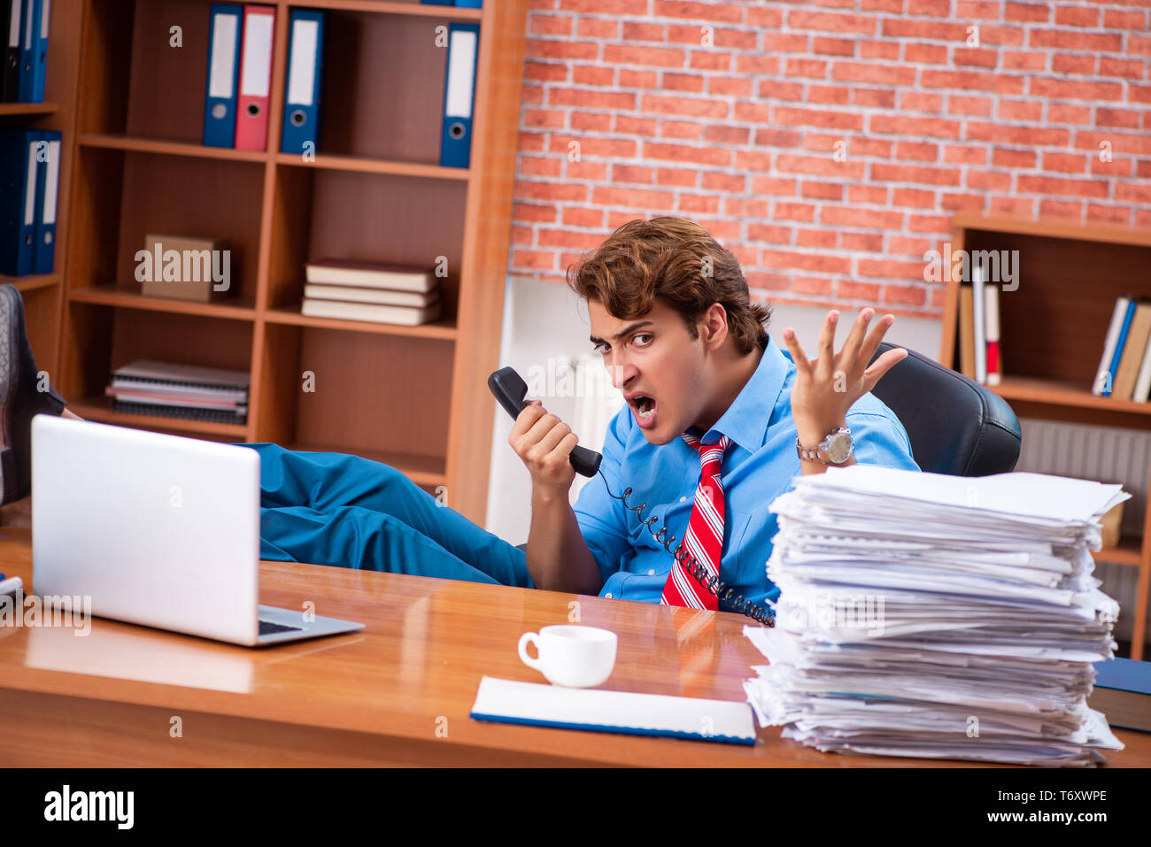Young employee with excessive work sitting at the office Stock Photo ...
