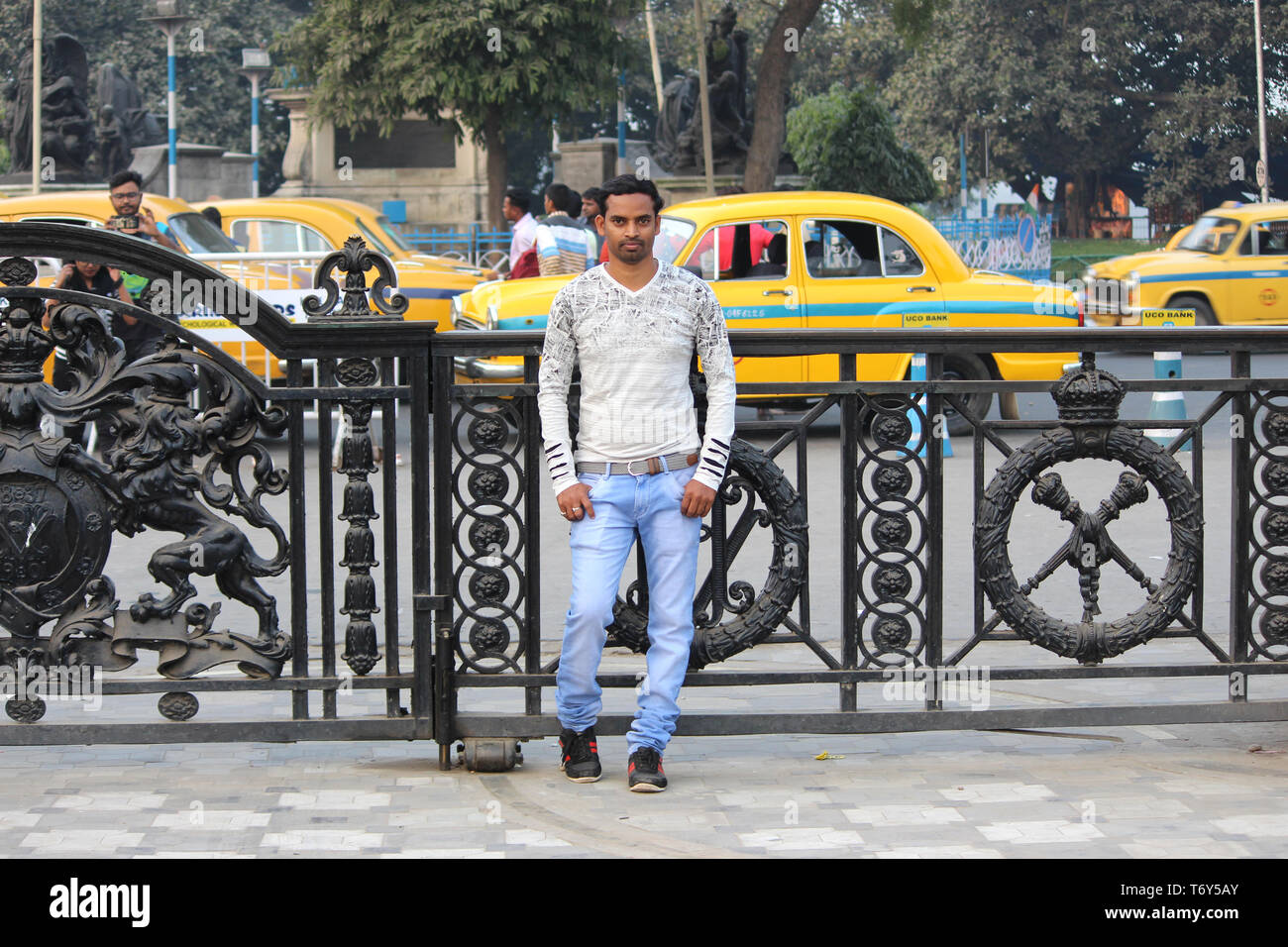 young man model standing infront of a gate with busy road background ...