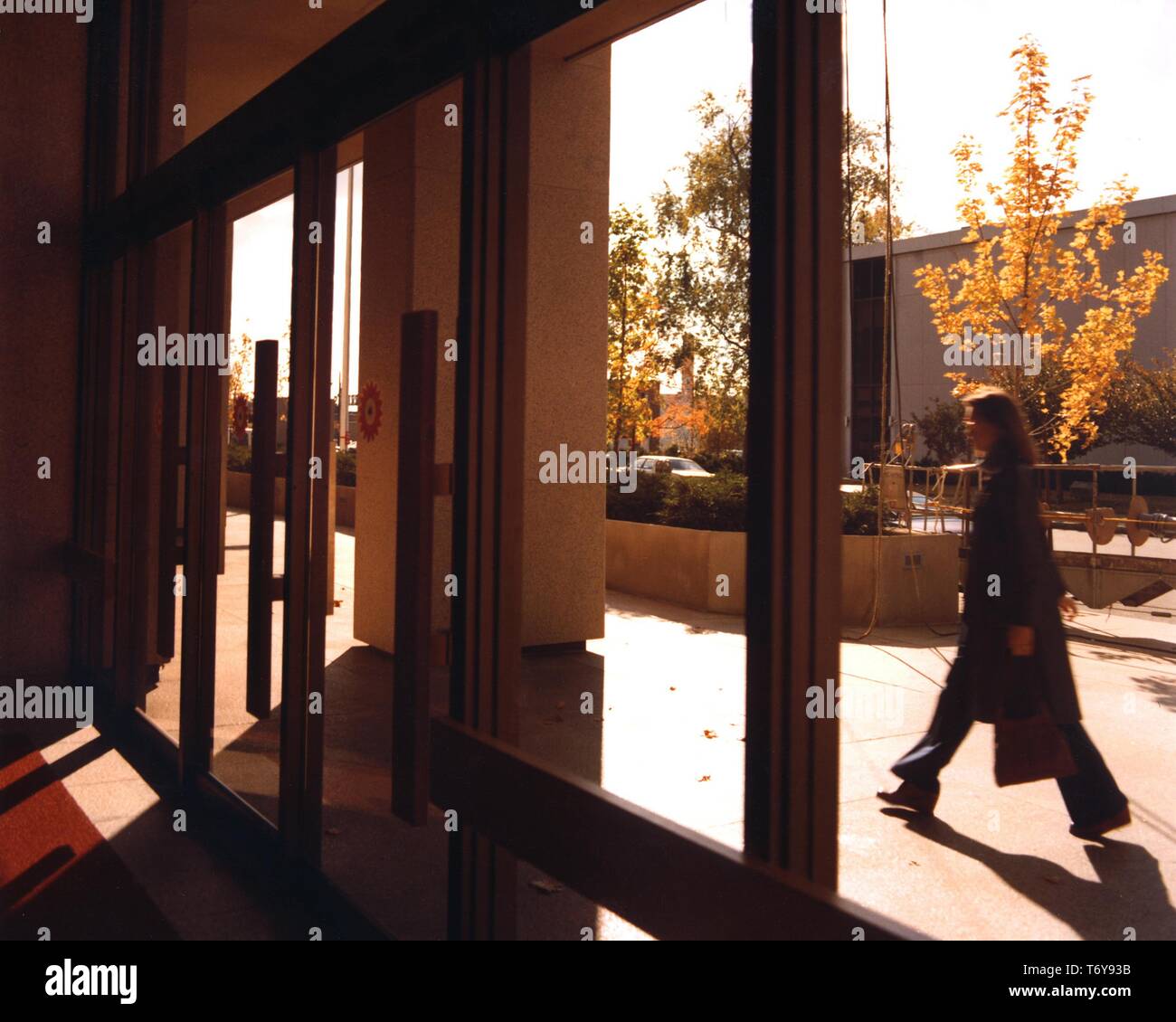Angled shot, through a lobby window, of a woman walking toward the main ...