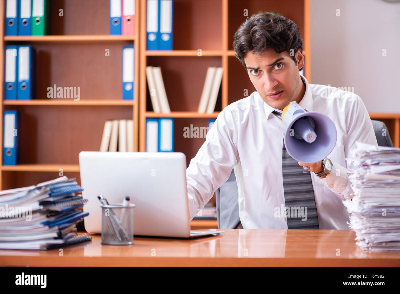 Young handsome businessman unhappy with excessive work Stock Photo - Alamy