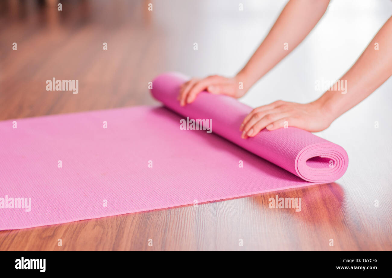 Hands woman folding yoga mat after workout at home. Woman rolling ...