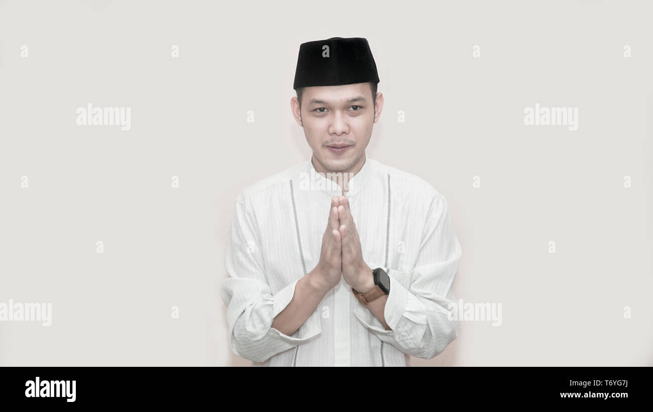 Portrait of cheerful young Asian muslim man smiling and greeting in ...