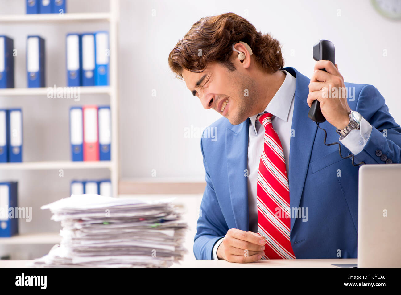 Deaf employee using hearing aid in office Stock Photo - Alamy
