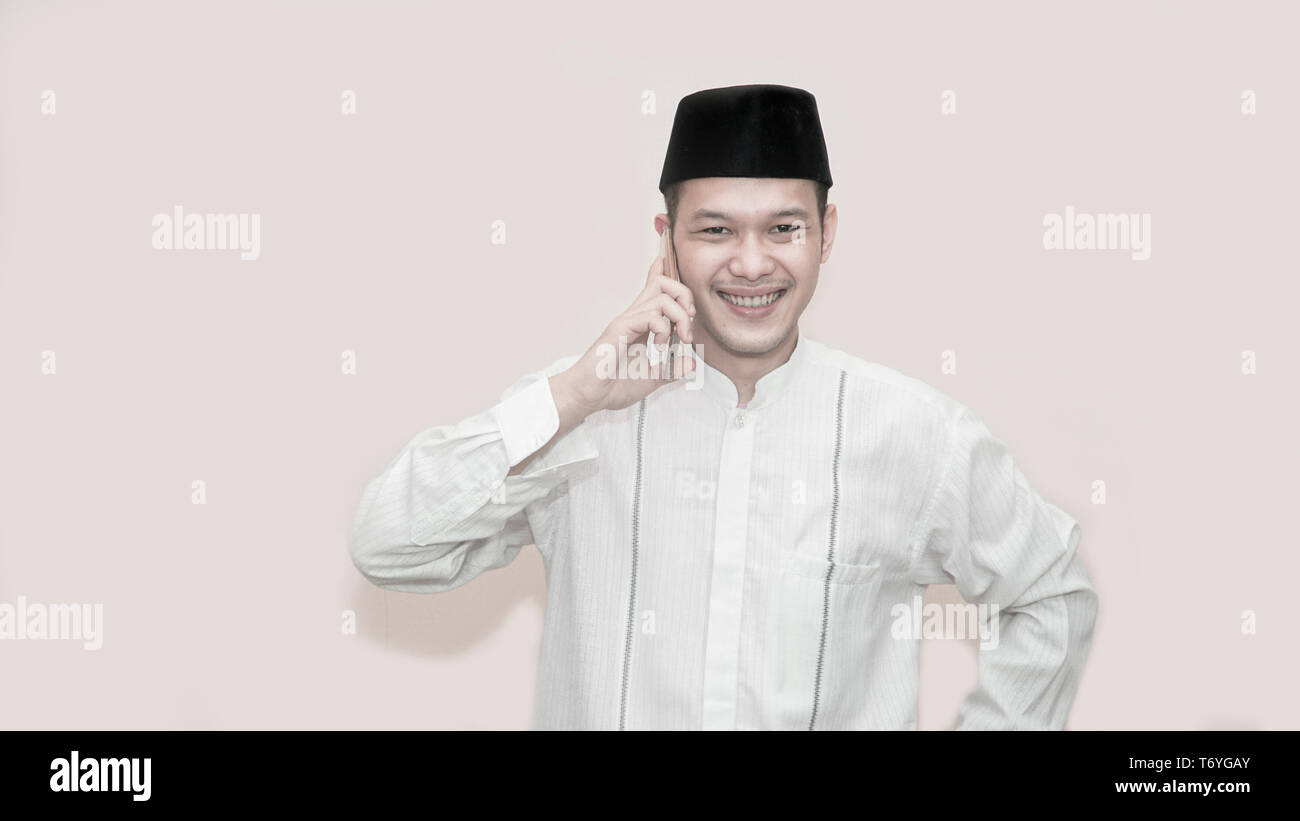 portrait of handsome asian muslim man with head cap and using ...