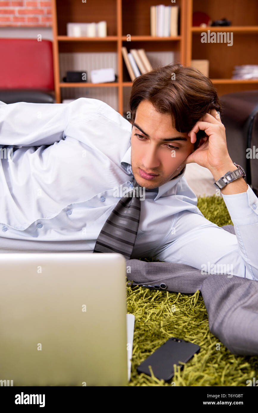 Young employee lying on the floor at office Stock Photo - Alamy