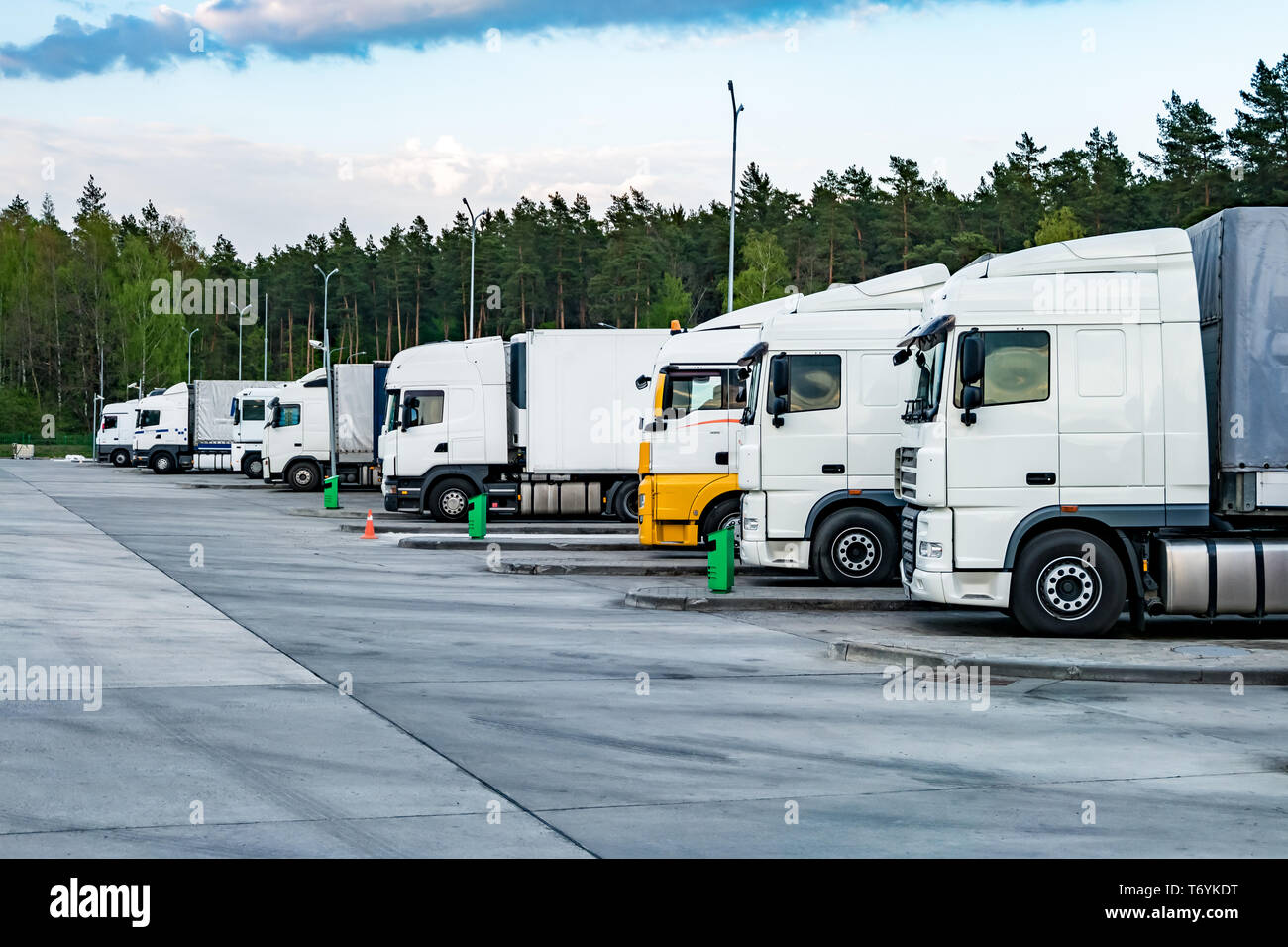 Trucks in a row with containers in the parking lot near forest ...