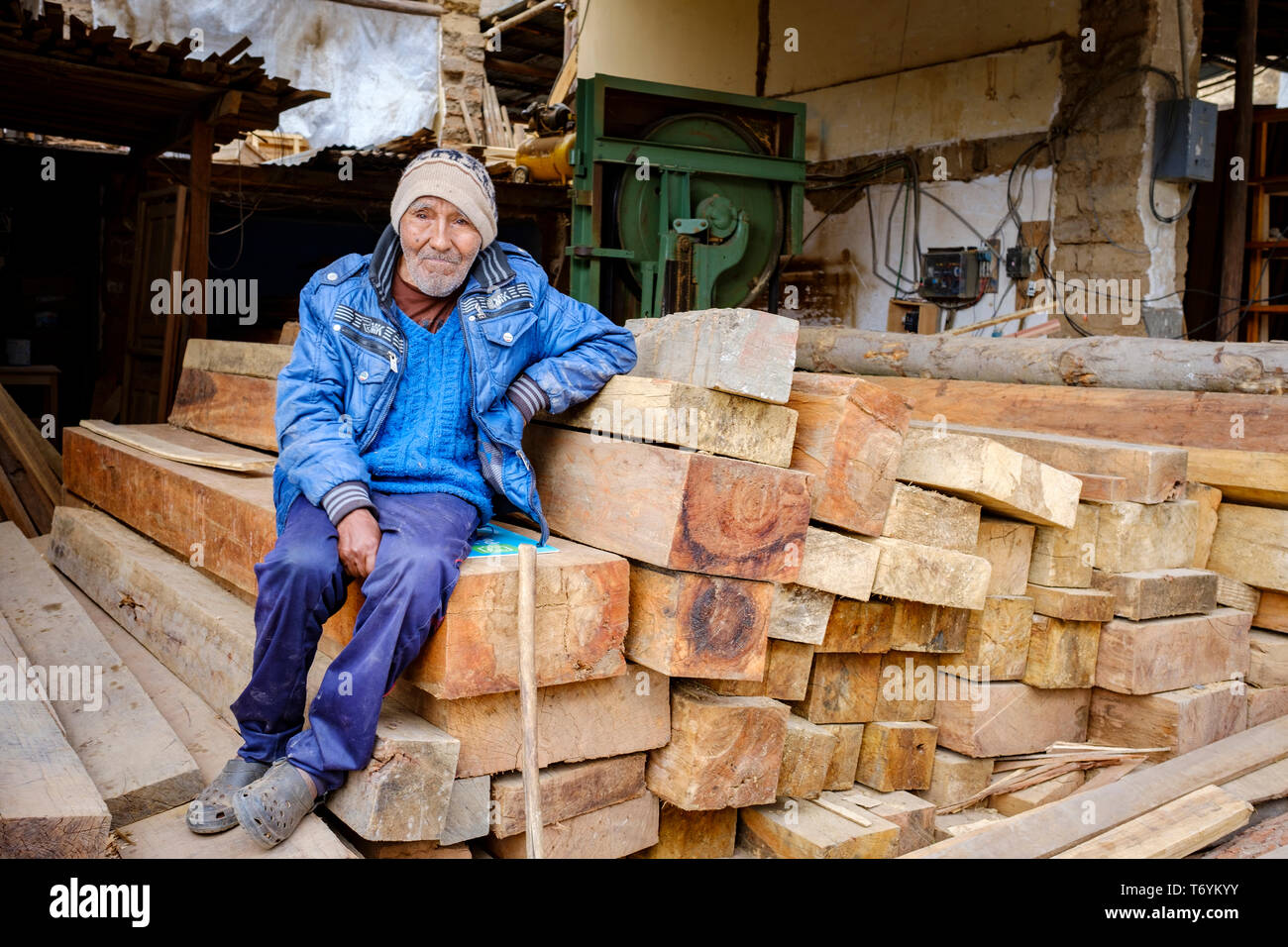 Portrait of Peruvian old man sitting on wooden beams, Paucartambo, Peru ...