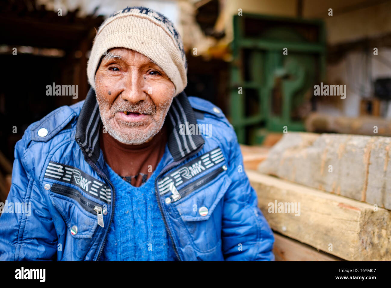 Portrait of Peruvian old man sitting on wooden beams, Paucartambo, Peru ...