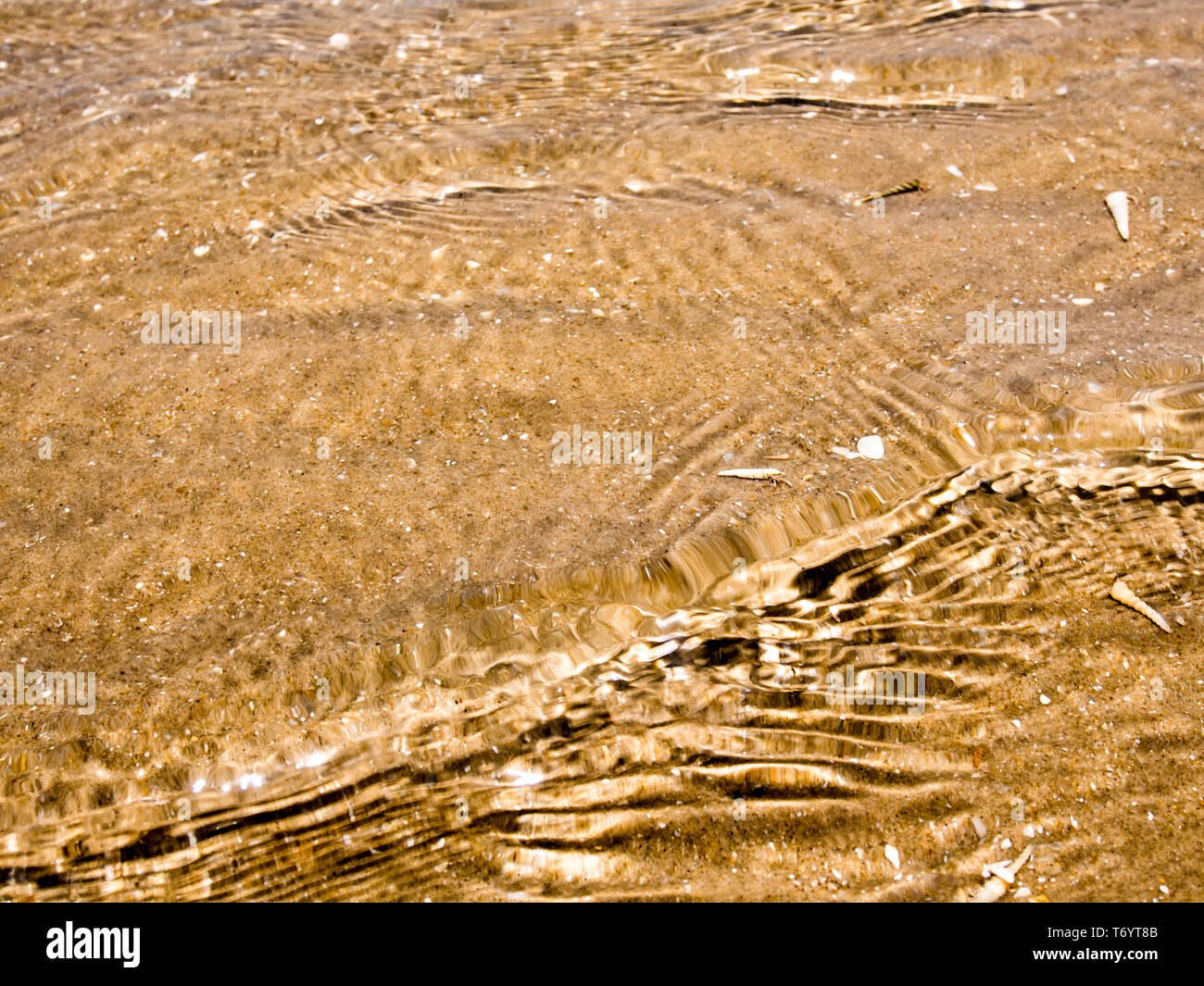 Reflection of sunlight on the moving sea water surface, sand beach and ...