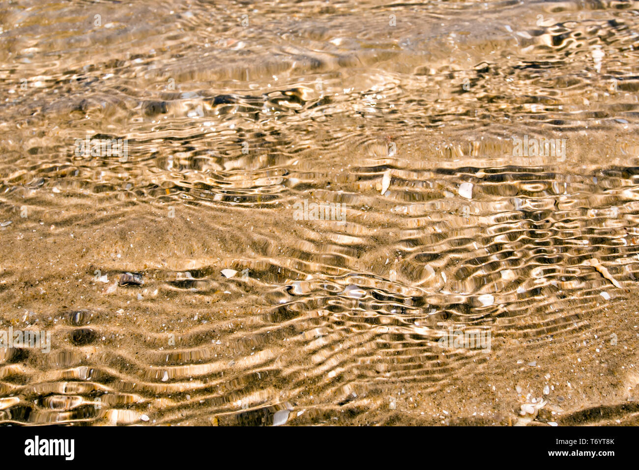 Reflection of sunlight on the moving sea water surface, sand beach and ...