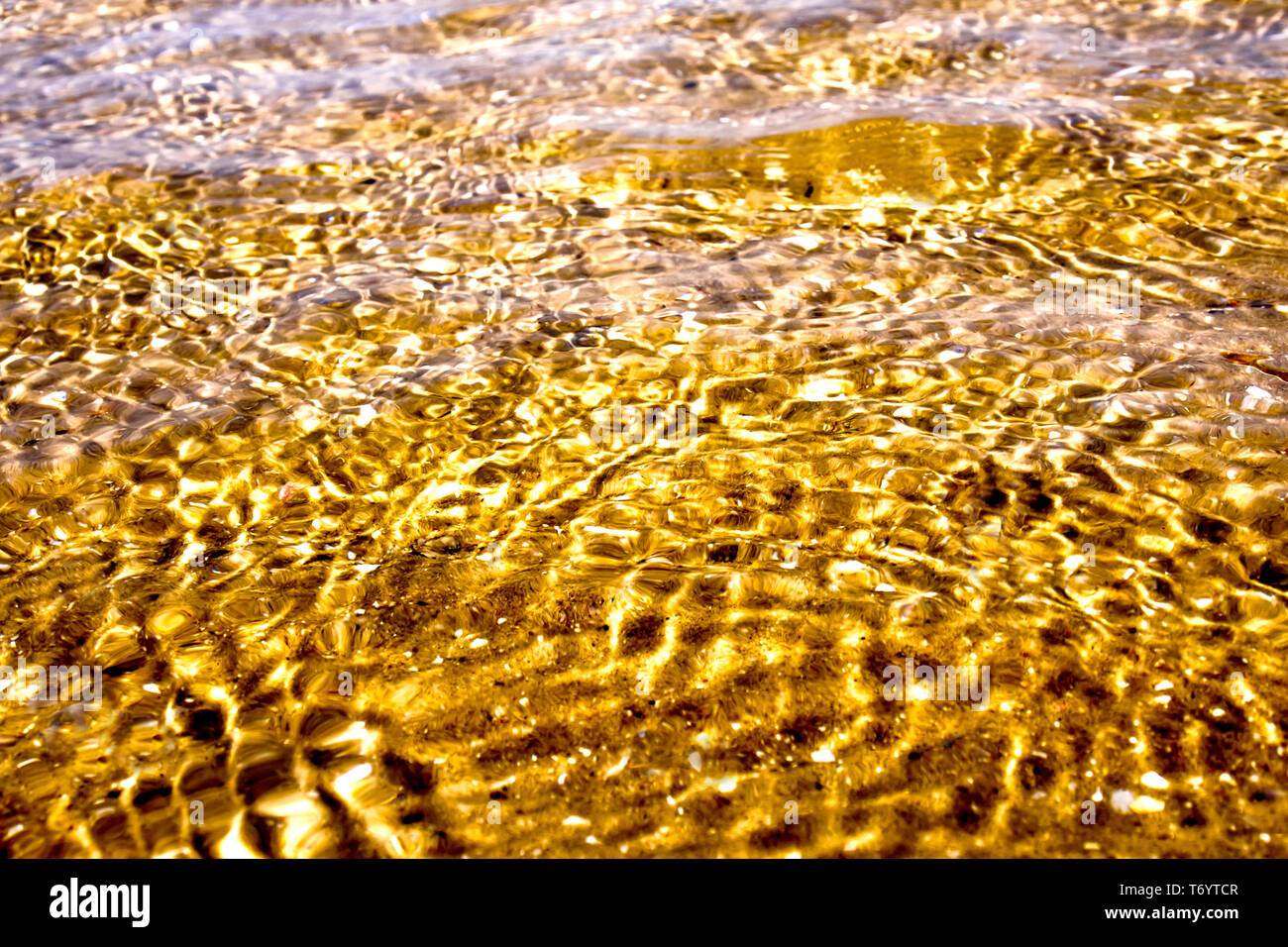 Reflection of sunlight on the moving sea water surface, sand beach and ...