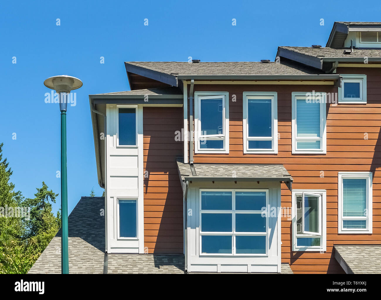 Corner of new townhouse with street light pole in front on blue sky ...
