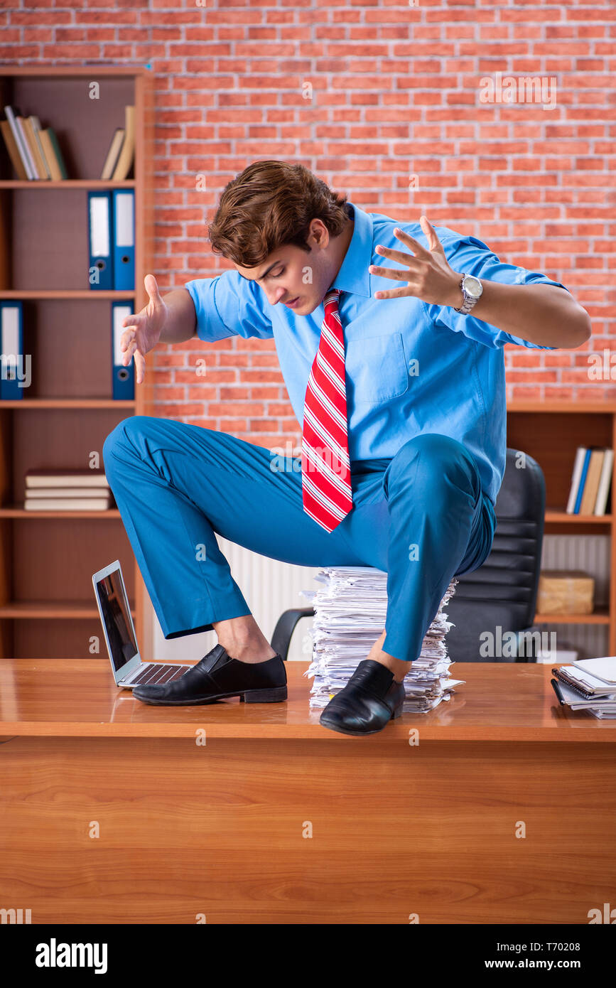 Young employee with excessive work sitting at the office Stock Photo ...