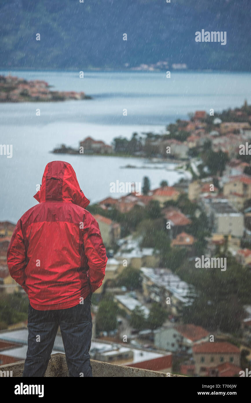 Man standing in a rain looking at Kotor town Stock Photo - Alamy