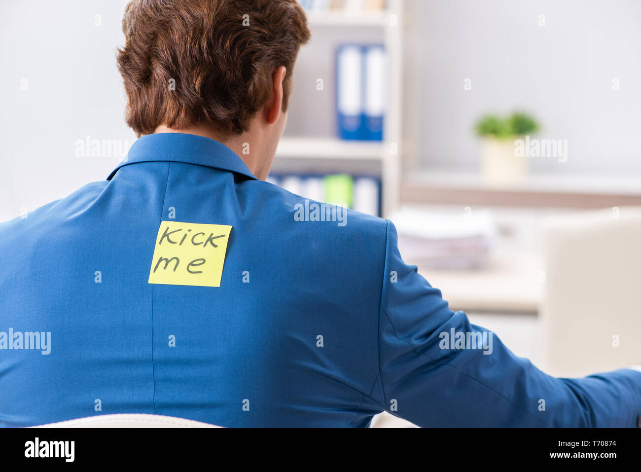 The office prank with kick me message on sticky note Stock Photo - Alamy