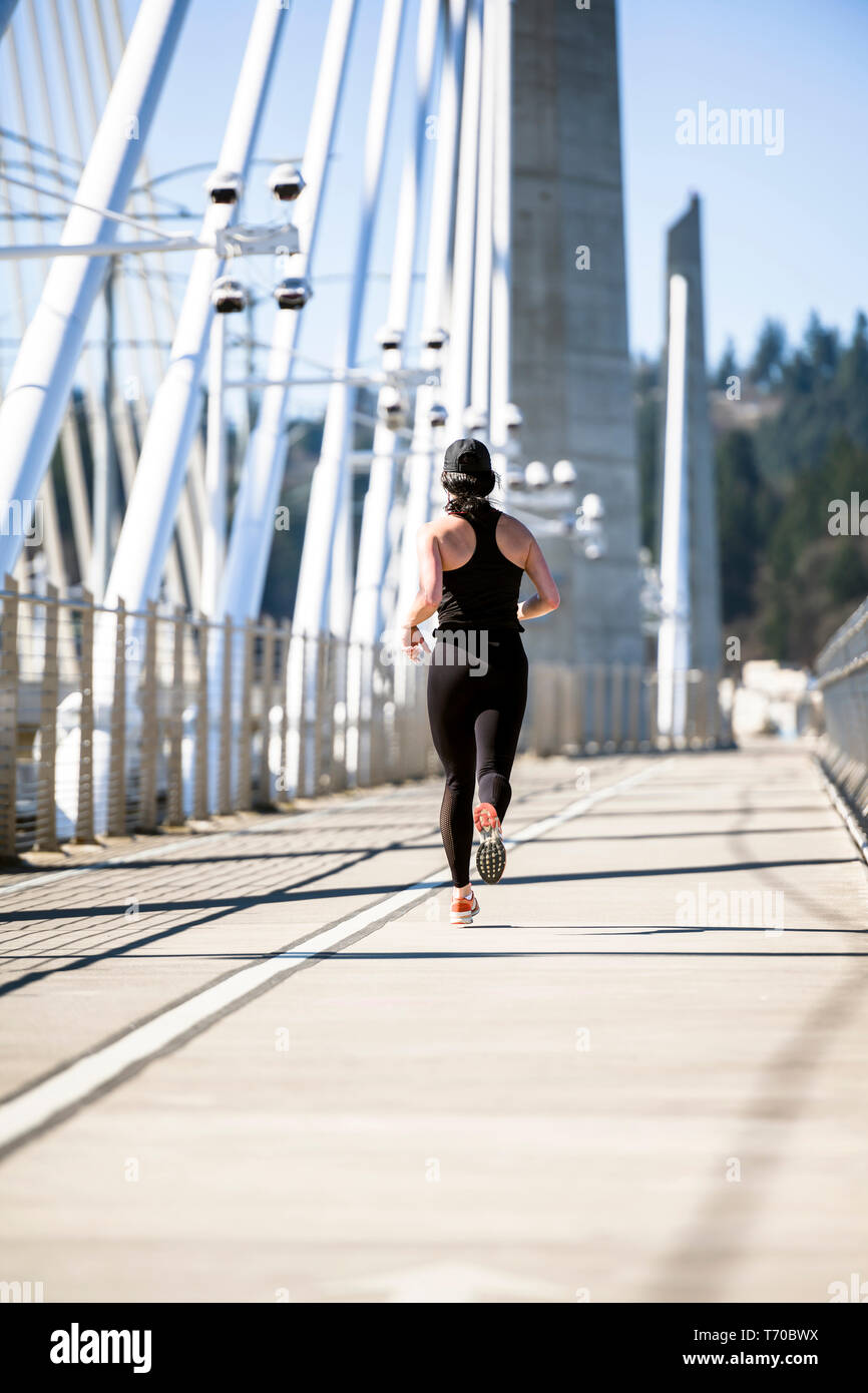 A girl in sportswear and a mobile gadget with headphones makes a run ...