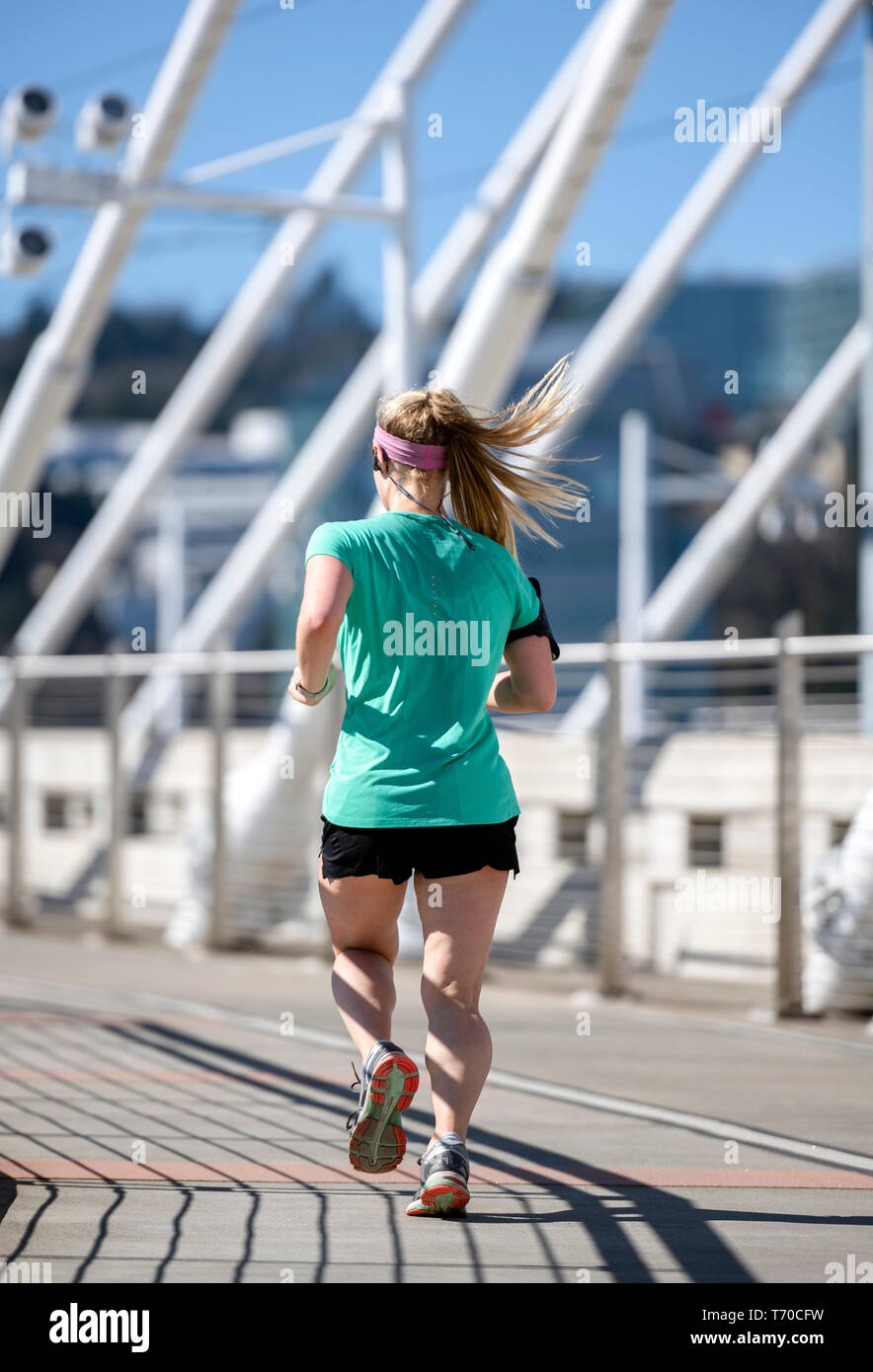 A girl in sportswear and a mobile gadget with headphones makes a run ...