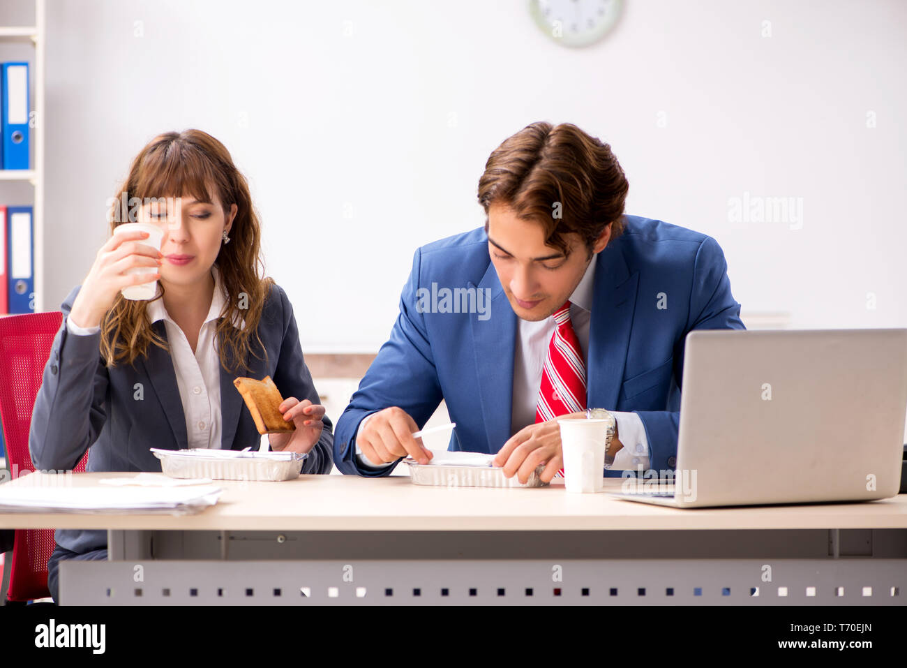 Two colleagues having lunch break at workplace Stock Photo - Alamy