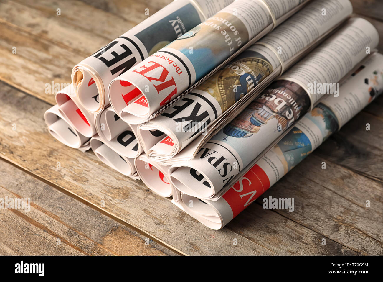 Rolled newspapers on wooden background Stock Photo - Alamy