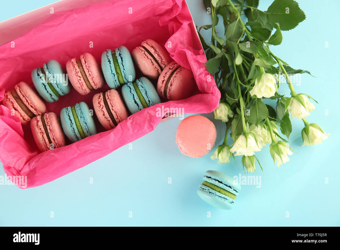 Delicious macarons and flowers on color background Stock Photo - Alamy