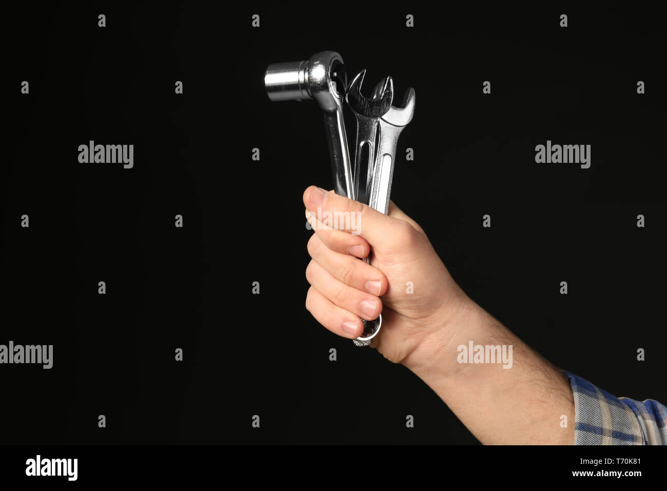 Car mechanic holding tools on black background Stock Photo - Alamy