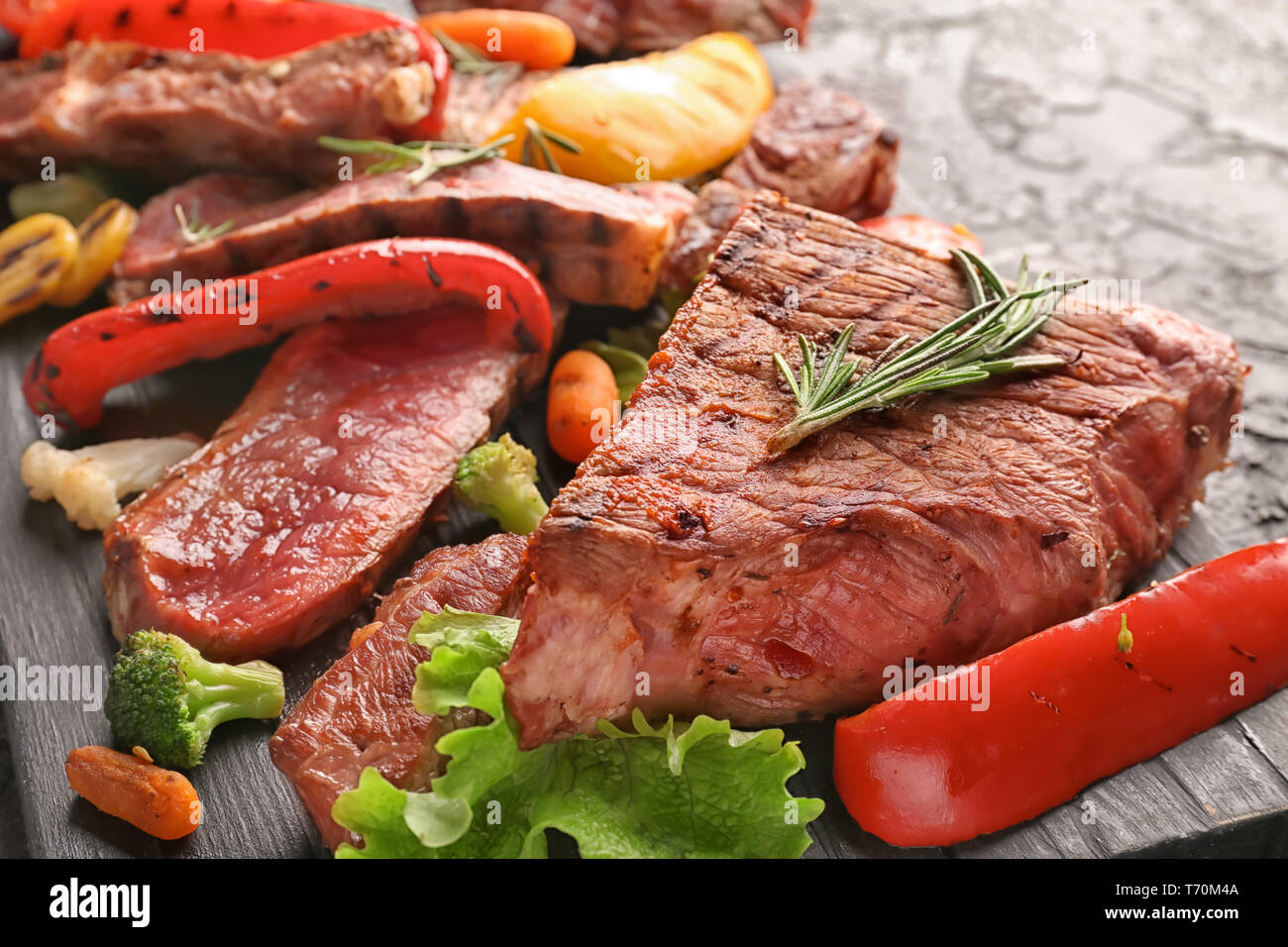 Meat with vegetable garnish on wooden board, closeup Stock Photo - Alamy