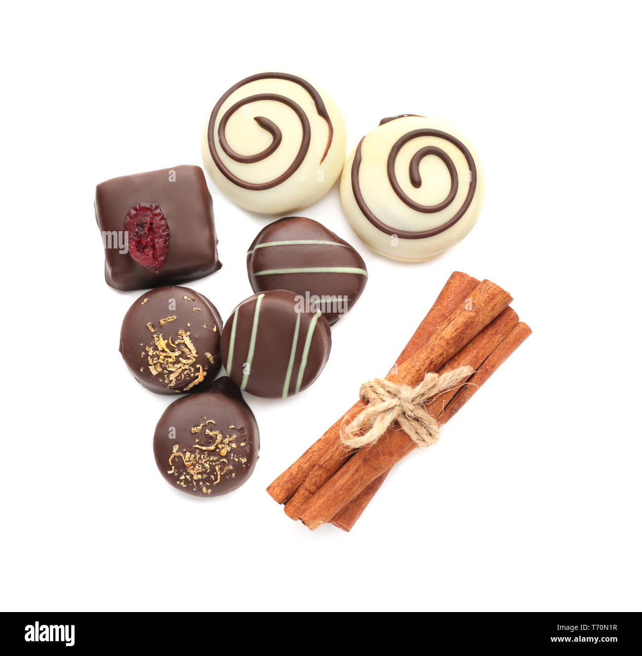 Tasty chocolate candies and cinnamon sticks on white background Stock ...