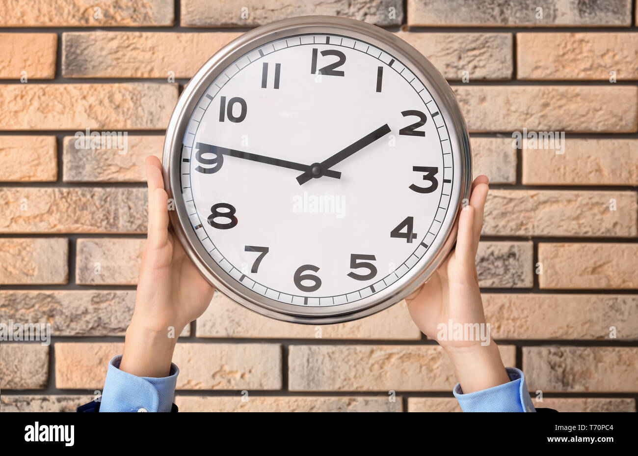 Man holding clock on brick background. Time management concept Stock ...