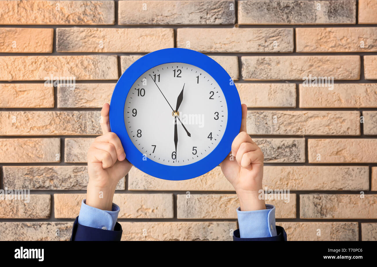 Man holding clock on brick background. Time management concept Stock ...