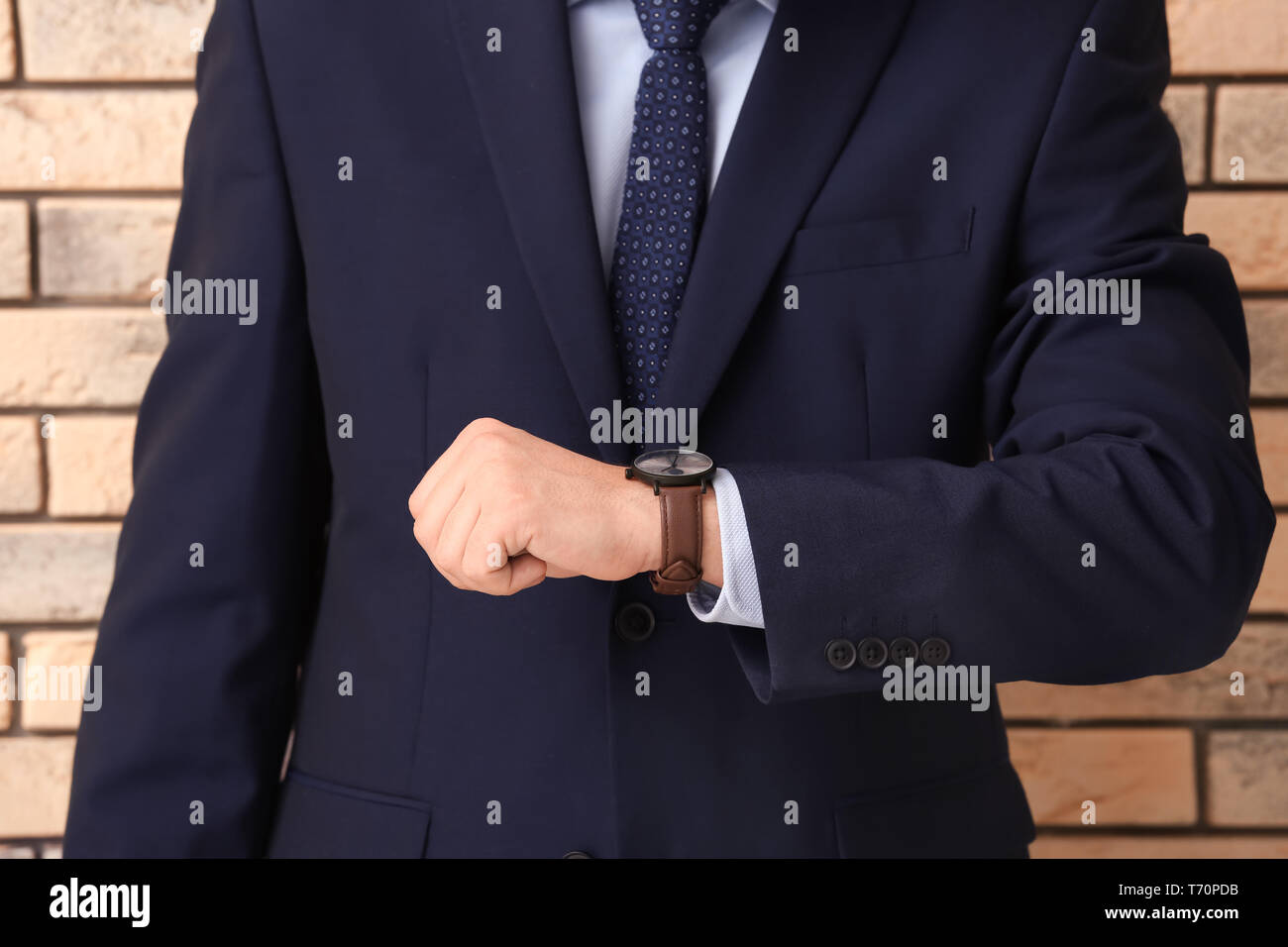 Man looking at his watch on brick background. Time management concept ...