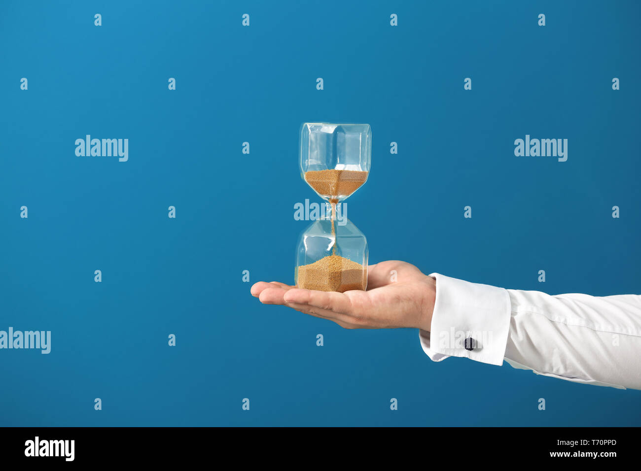 Man holding hourglass on color background. Time management concept ...