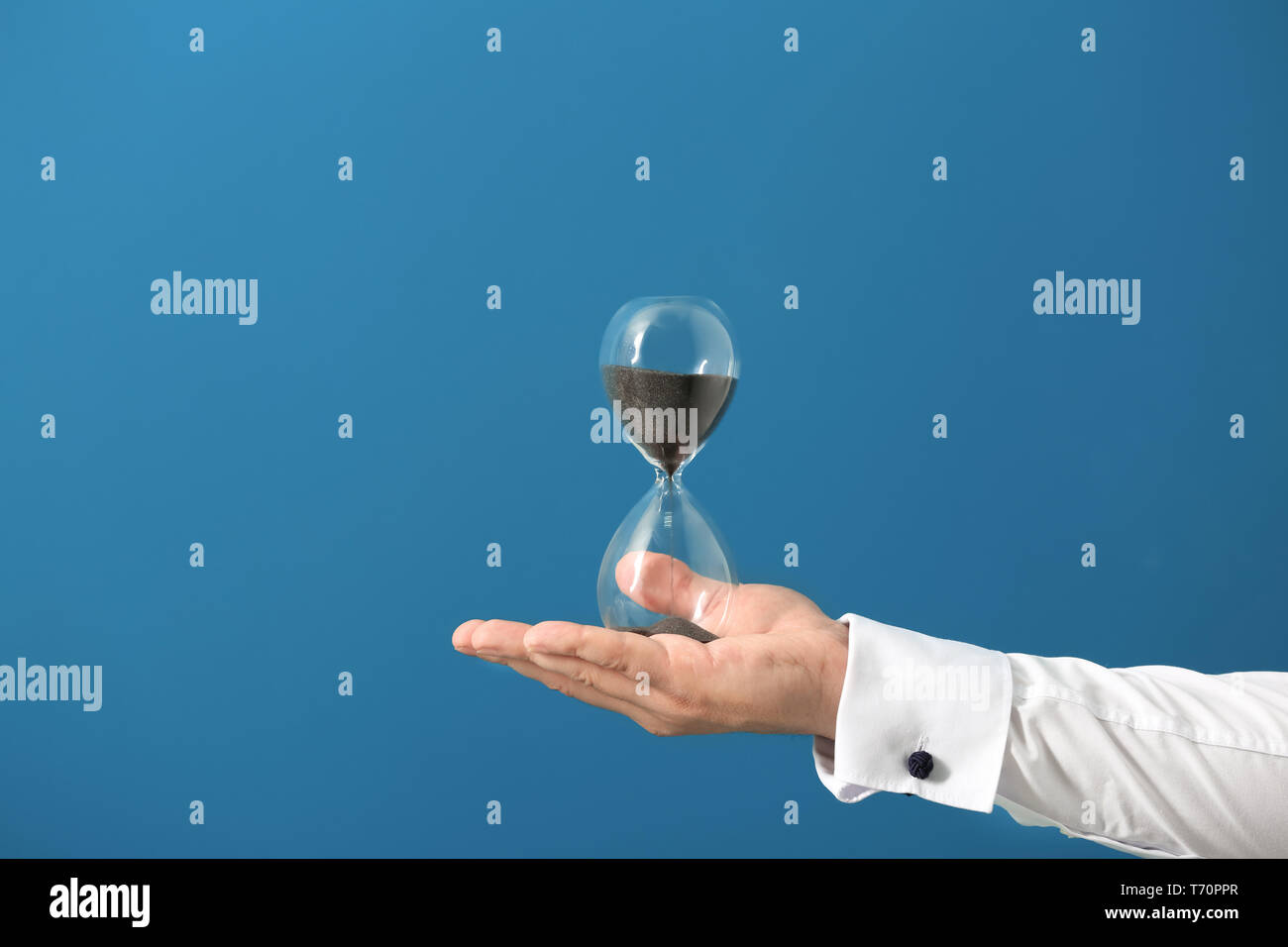 Man holding hourglass on color background. Time management concept ...