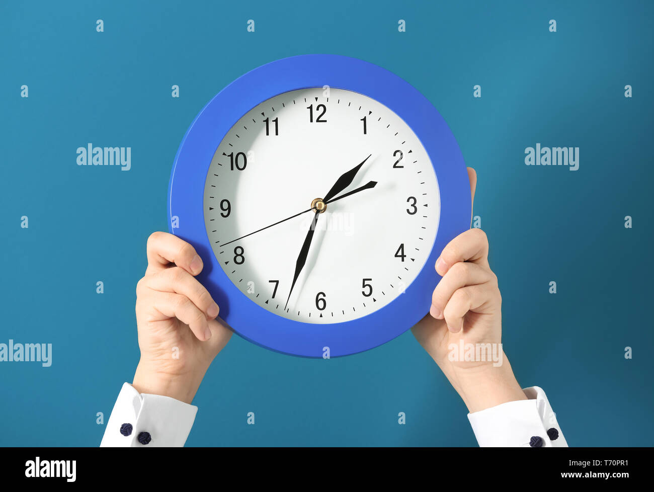 Man holding clock on color background. Time management concept Stock ...