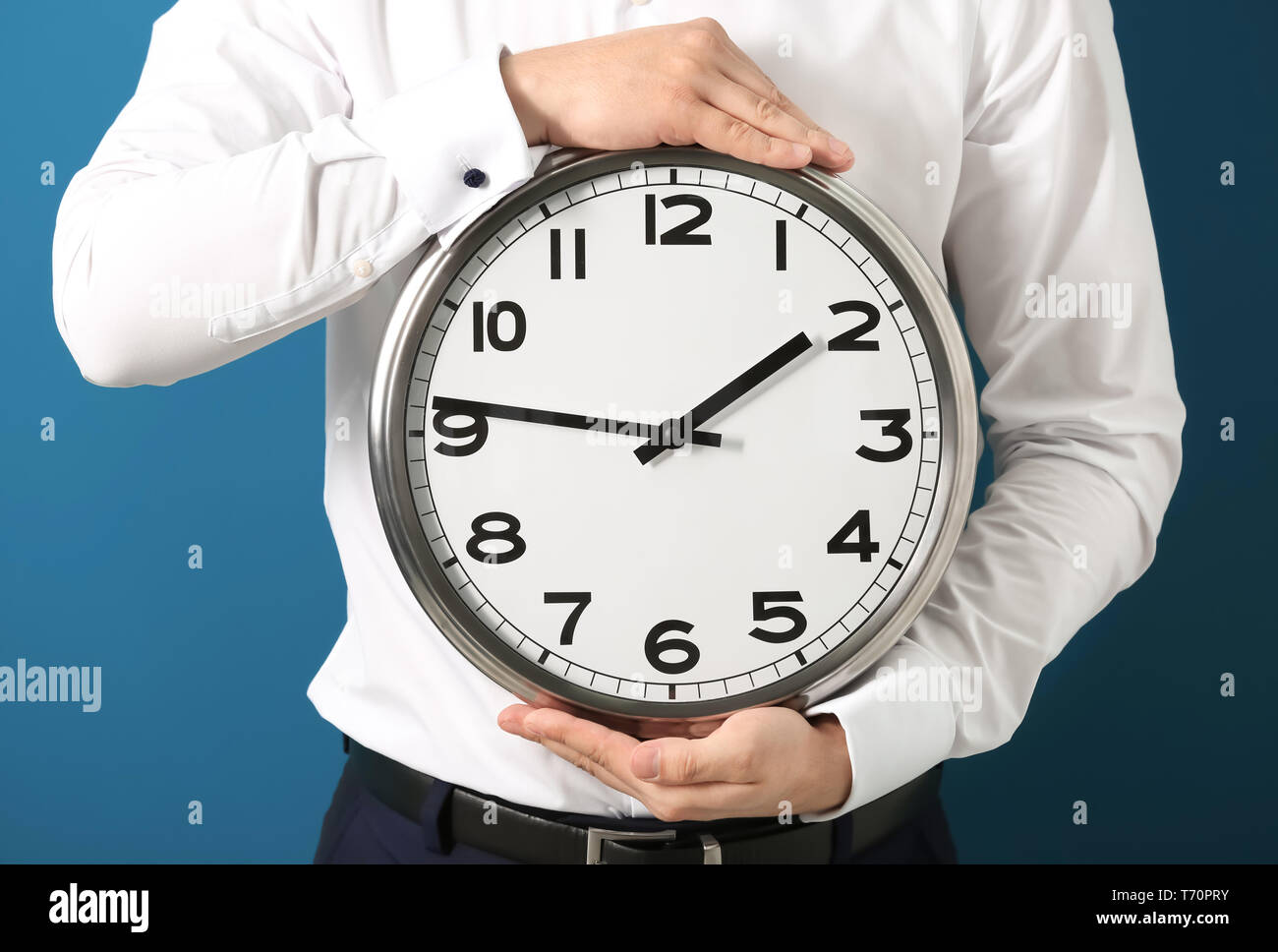 Man holding clock on color background. Time management concept Stock ...