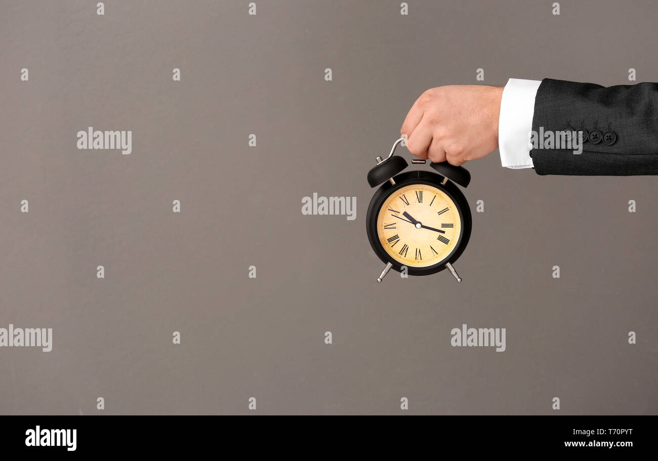 Man holding alarm clock on gray background. Time management concept ...