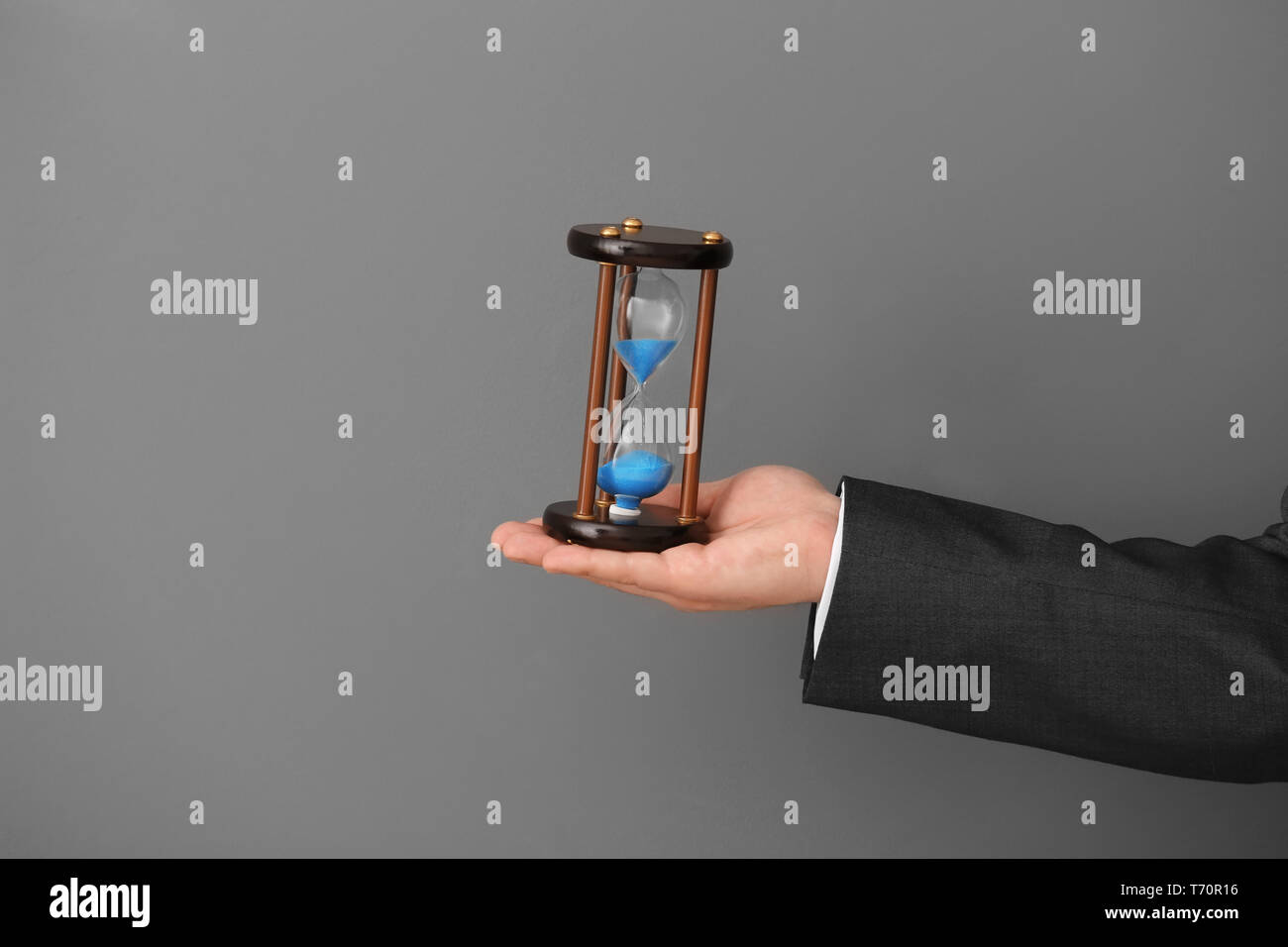 Man holding hourglass on gray background. Time management concept Stock ...