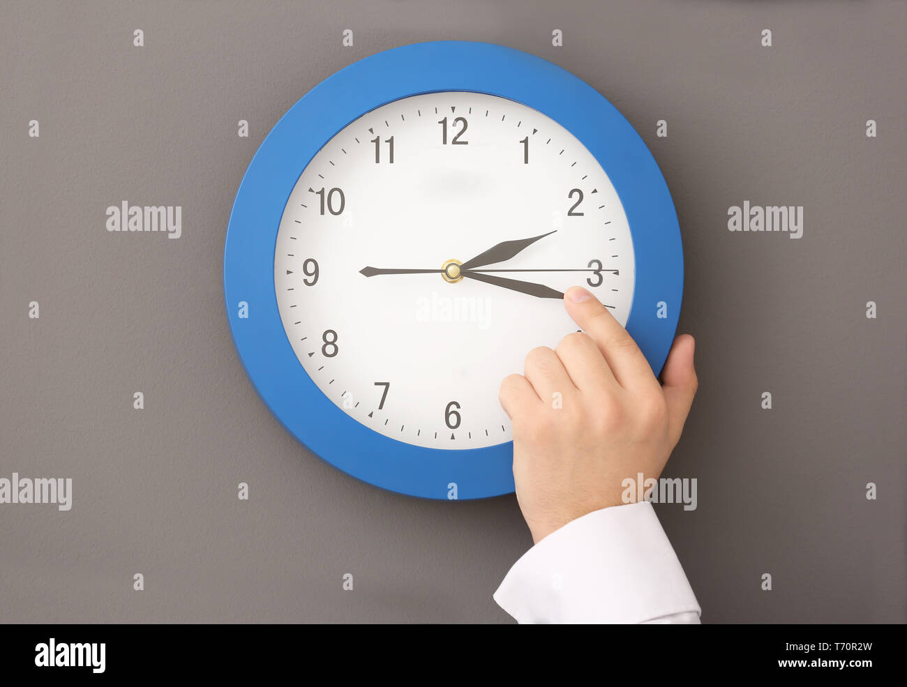 Man pointing on clock against gray background. Time management concept ...