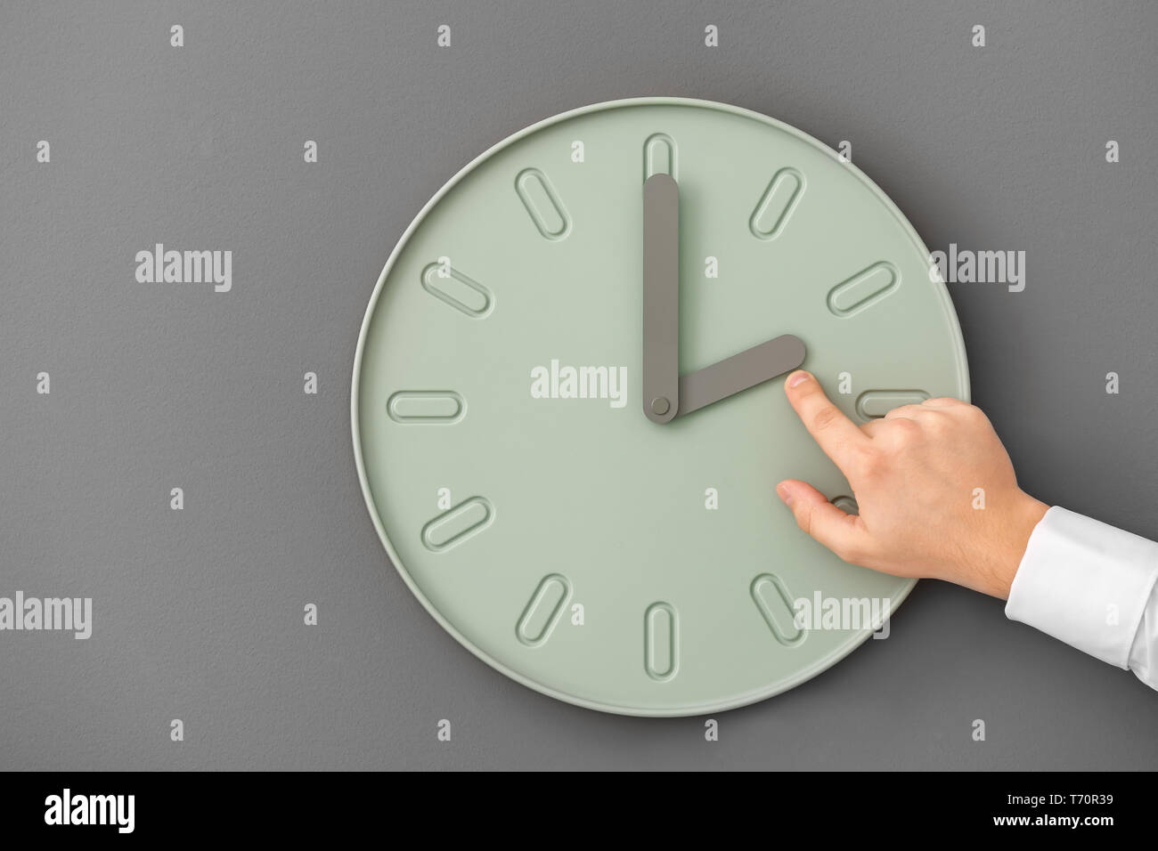 Man pointing on clock against gray background. Time management concept ...