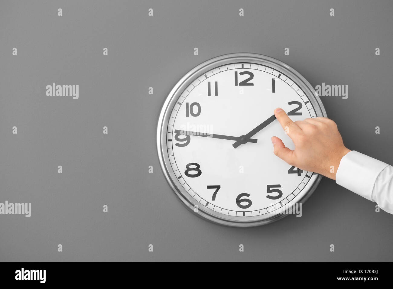 Man pointing on clock against gray background. Time management concept ...