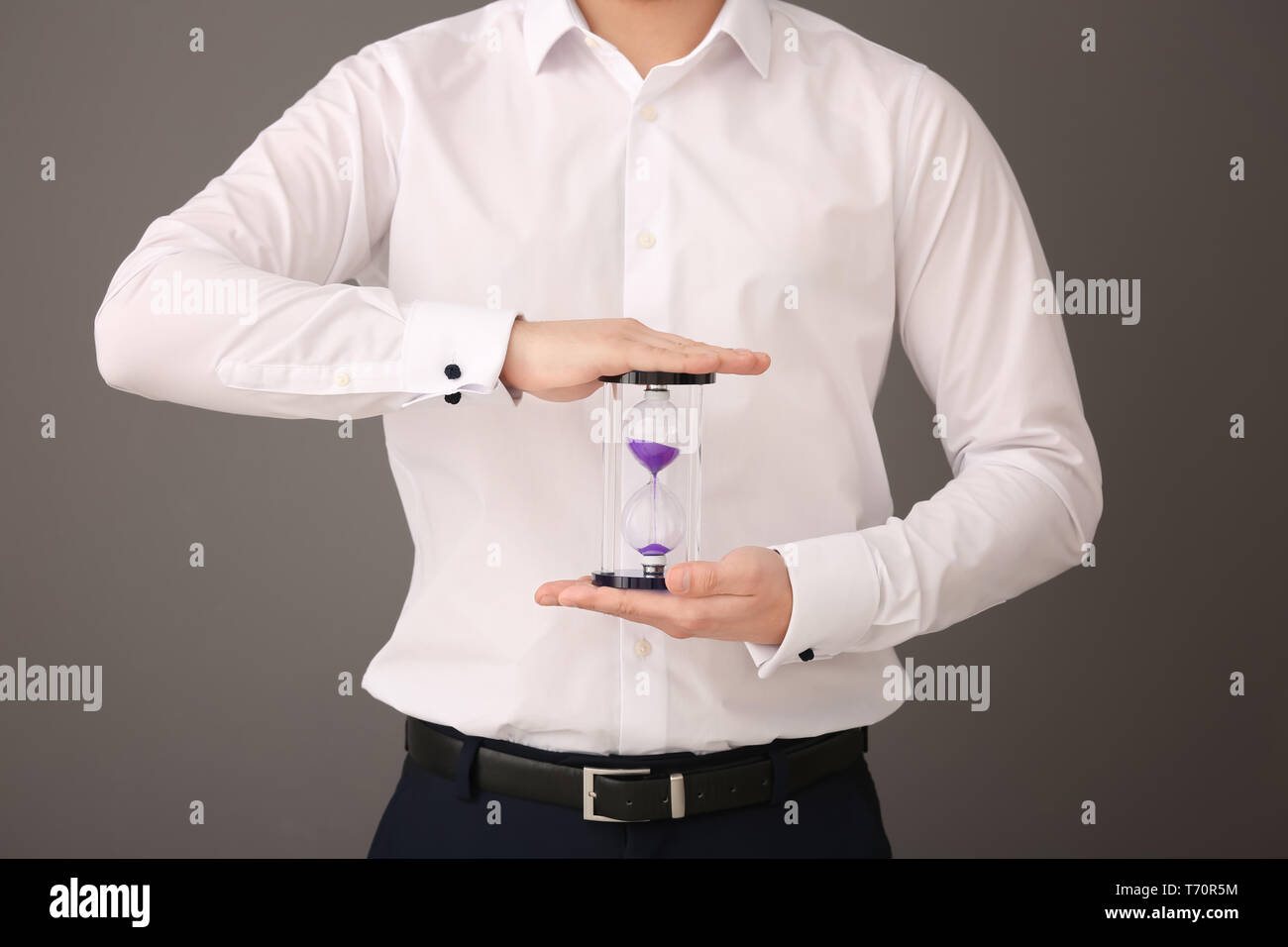 Man holding hourglass on gray background. Time management concept Stock ...