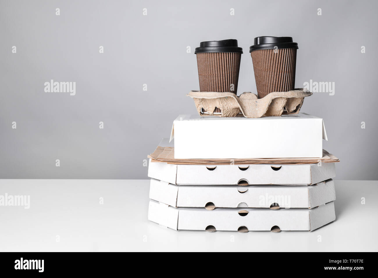 Different packages and carton cups on table against color background ...