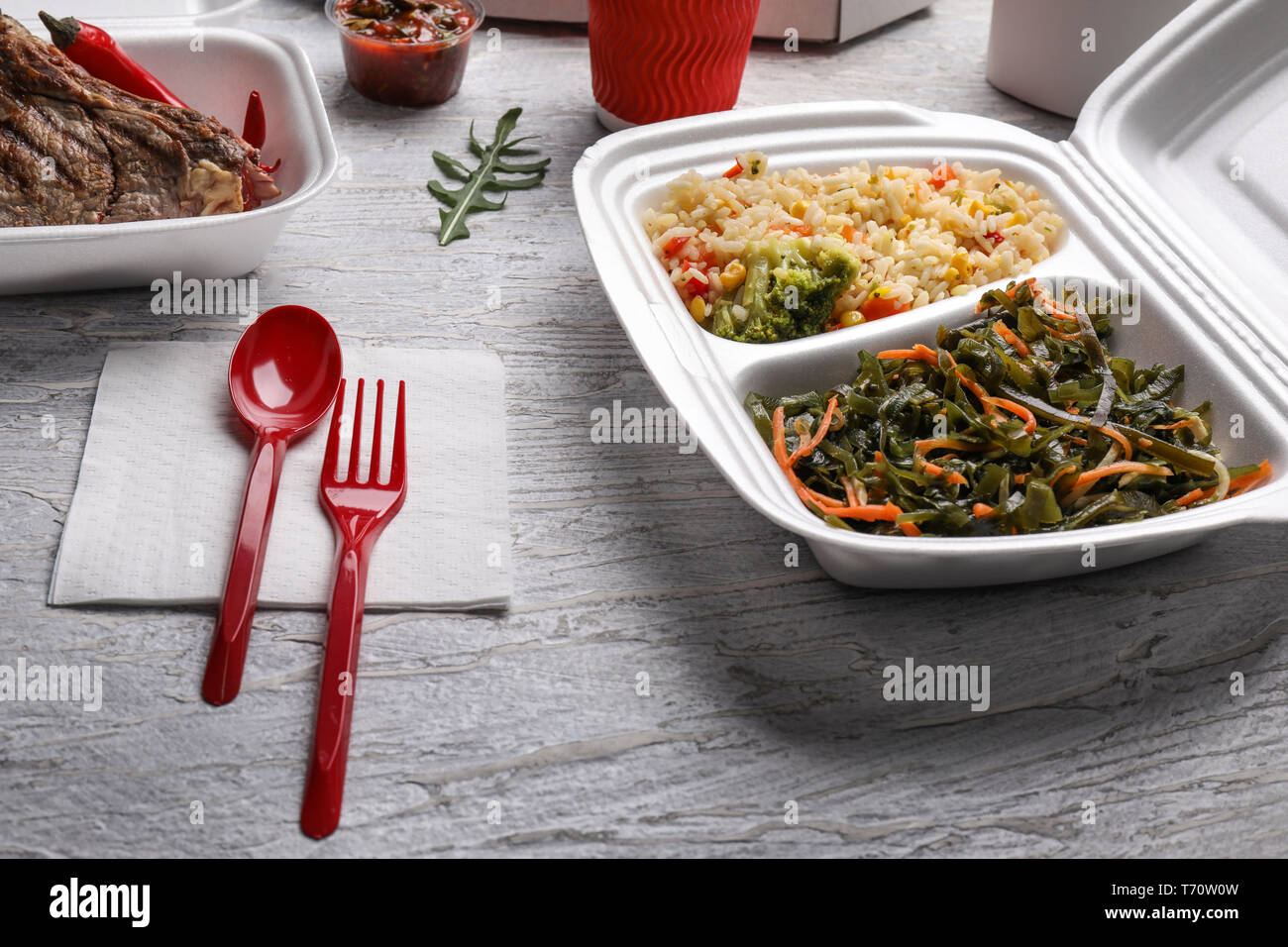 Container with delicious food on wooden table. Delivery service Stock ...