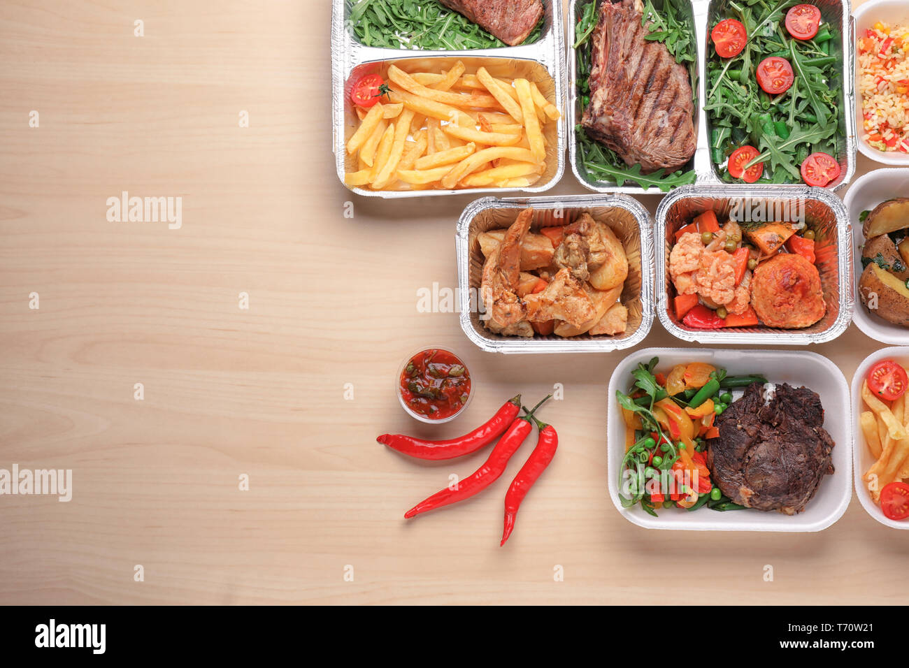 Different containers with delicious food on wooden table. Delivery ...