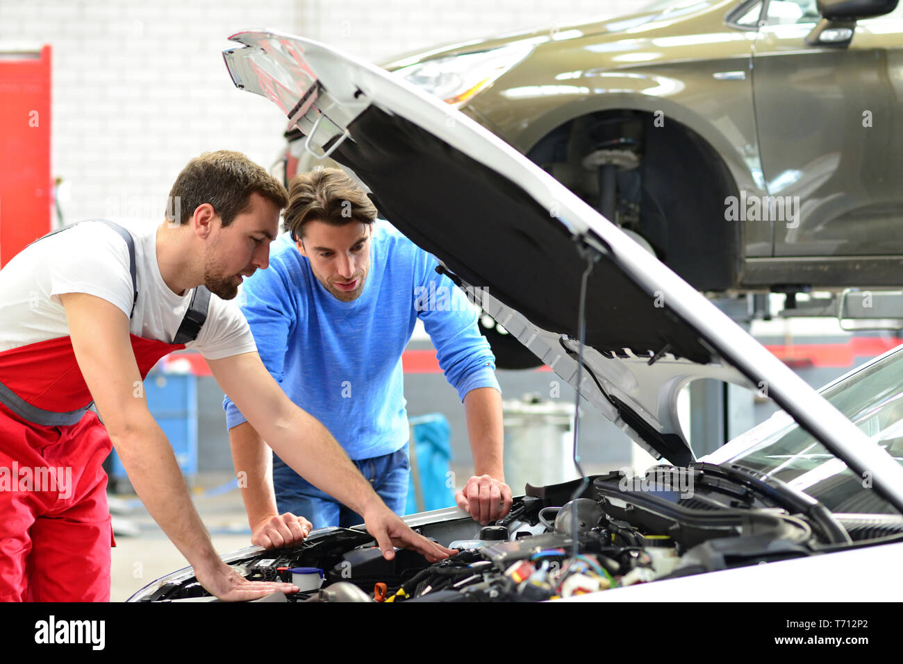 after-sales service in the car repair shop - mechanic and man talk ...