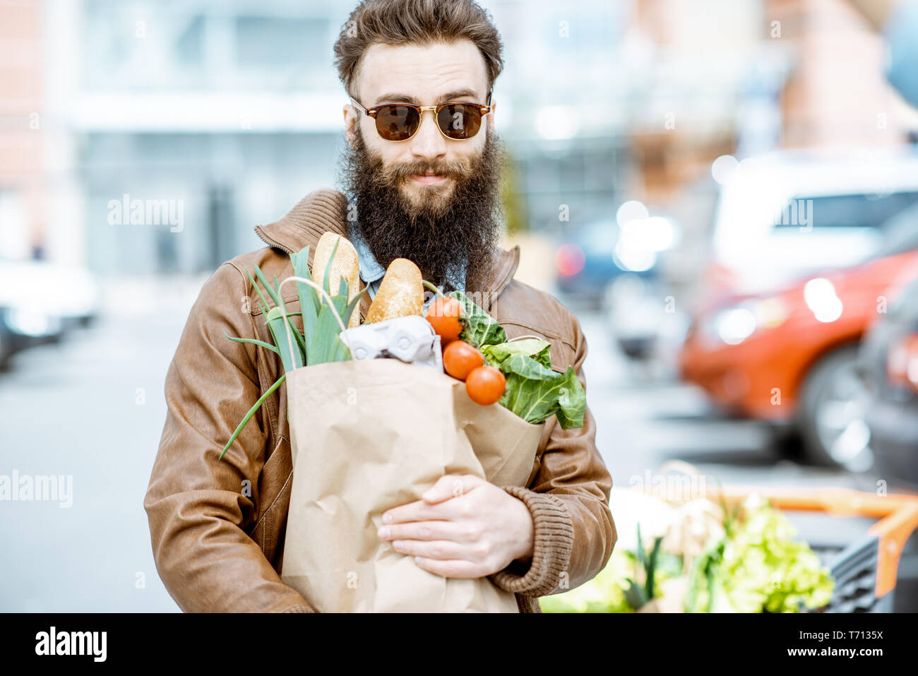 Happy stylish man with shopping bags full of fresh and healthy food ...