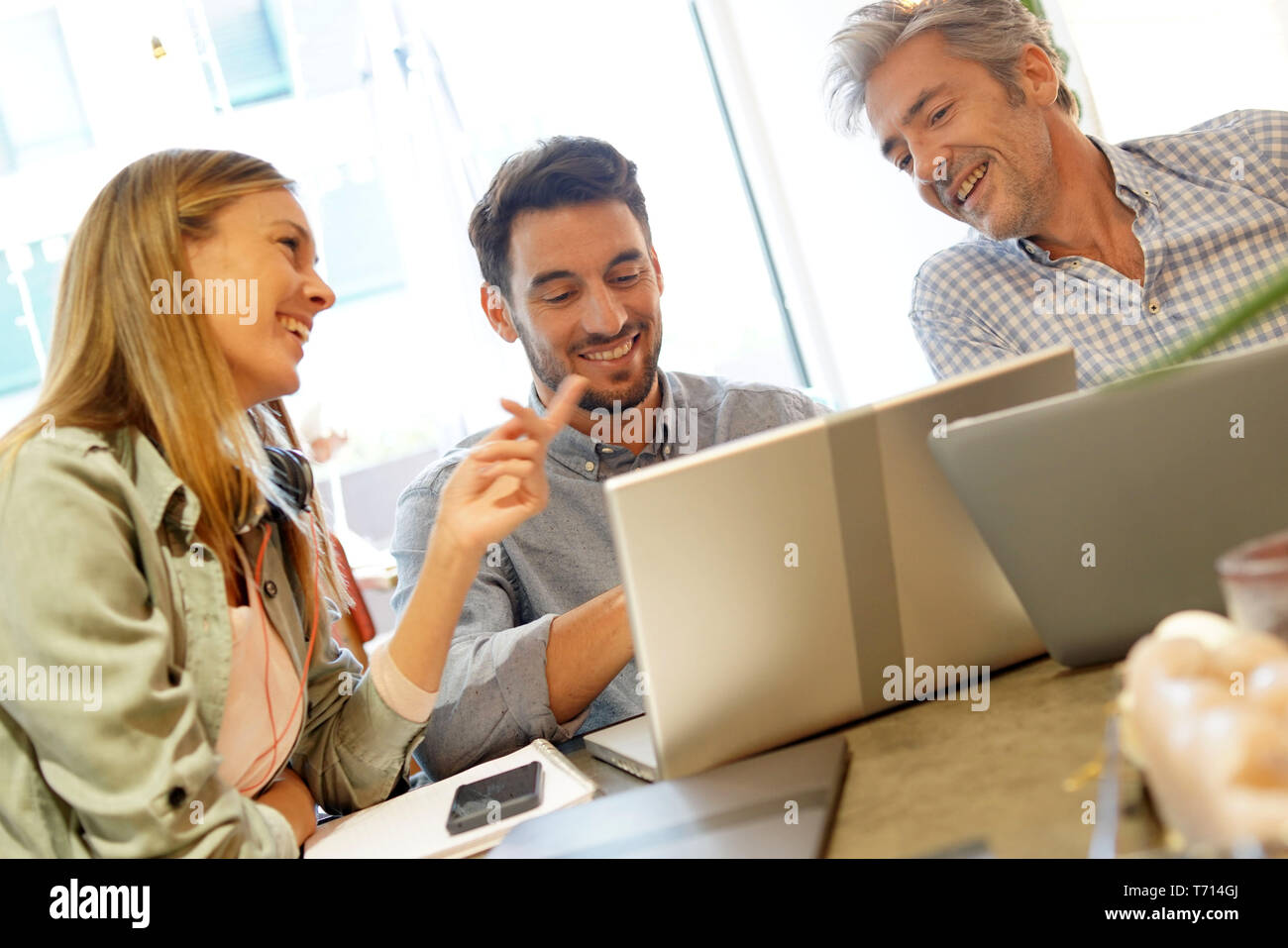 Colleagues laughing together in coworking space Stock Photo - Alamy