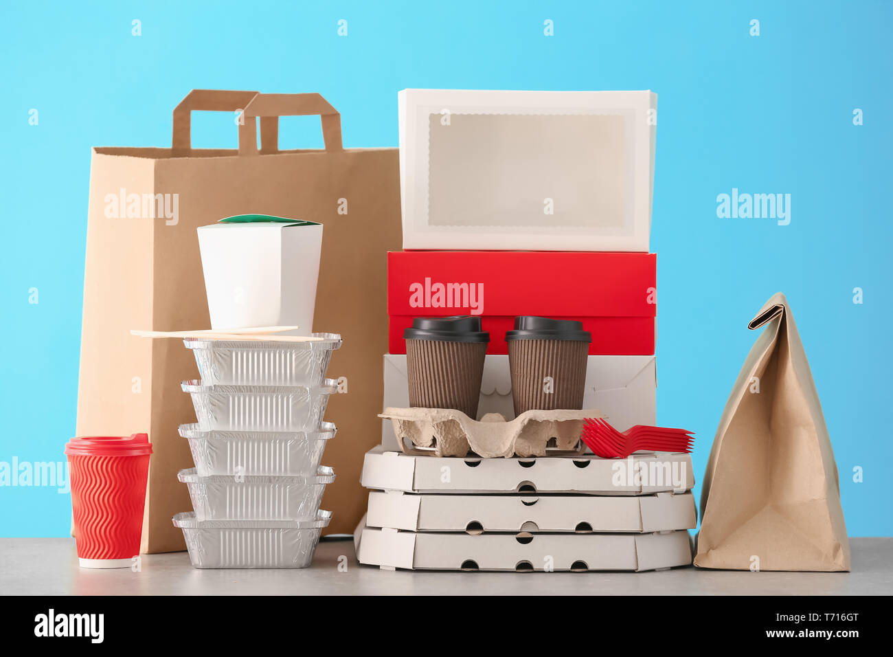 Different packages on table against color background. Food delivery ...