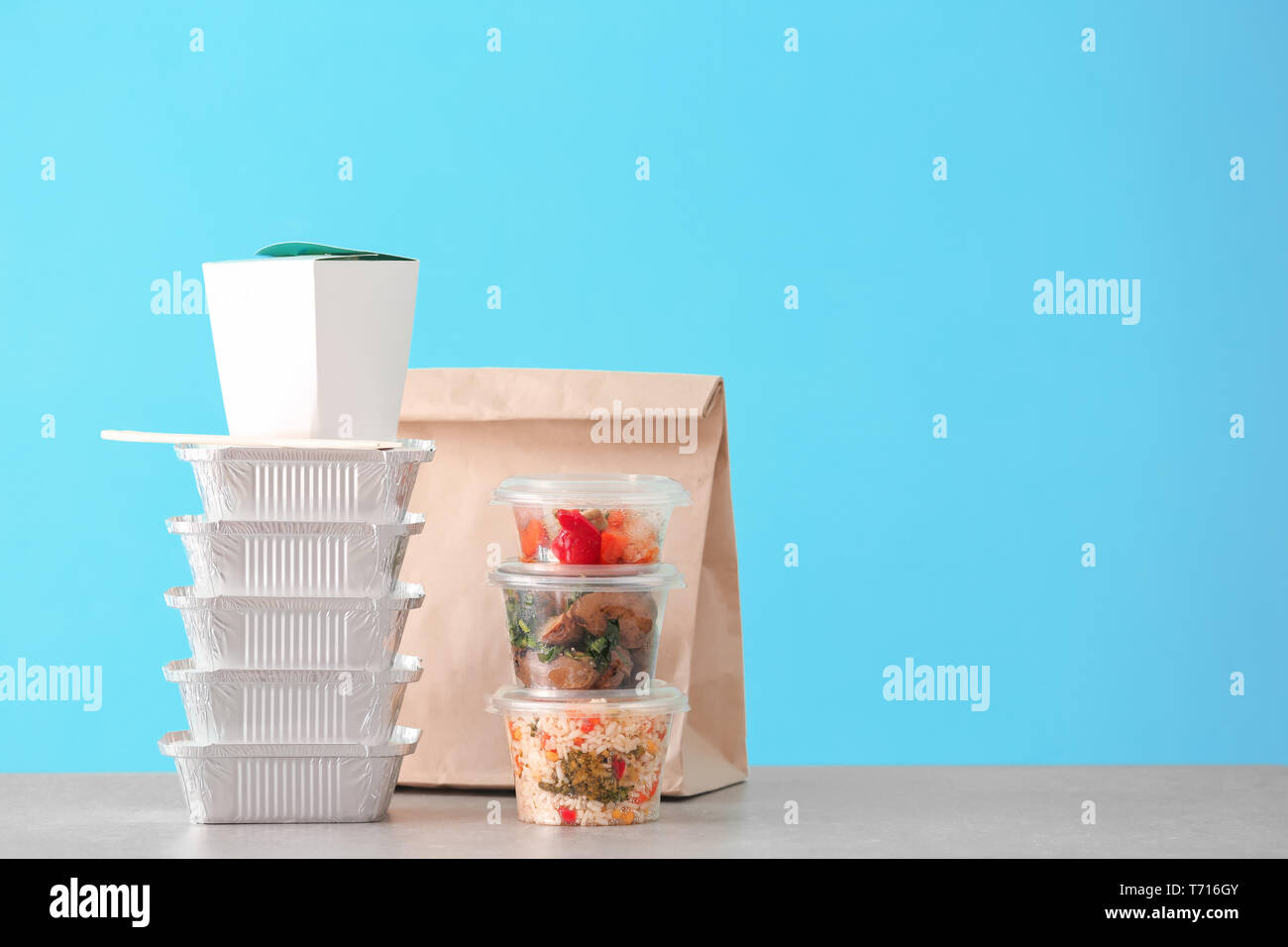 Different packages with delicious food on table against color ...