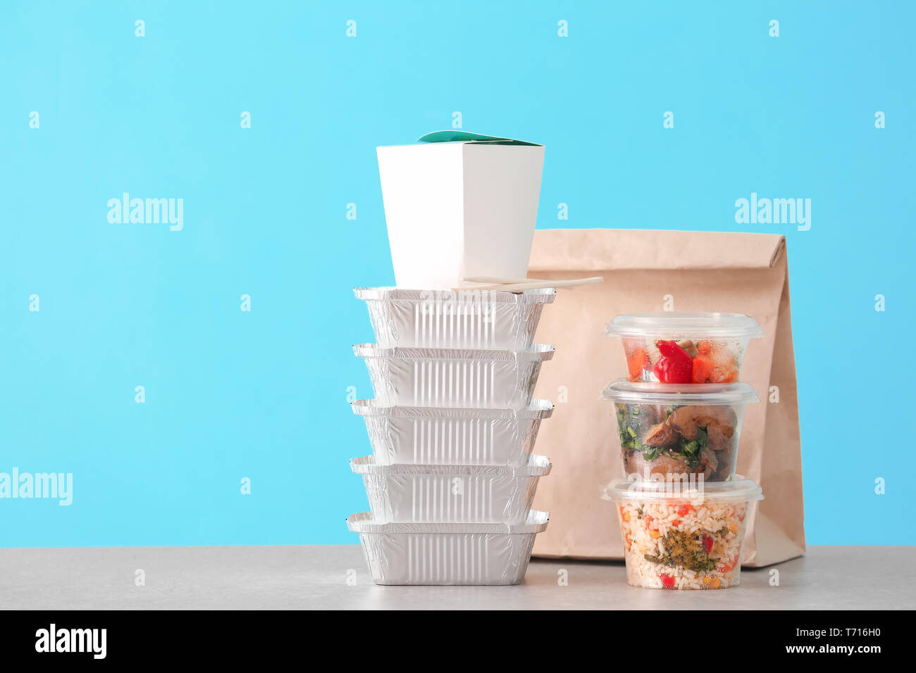 Different packages with delicious food on table against color ...