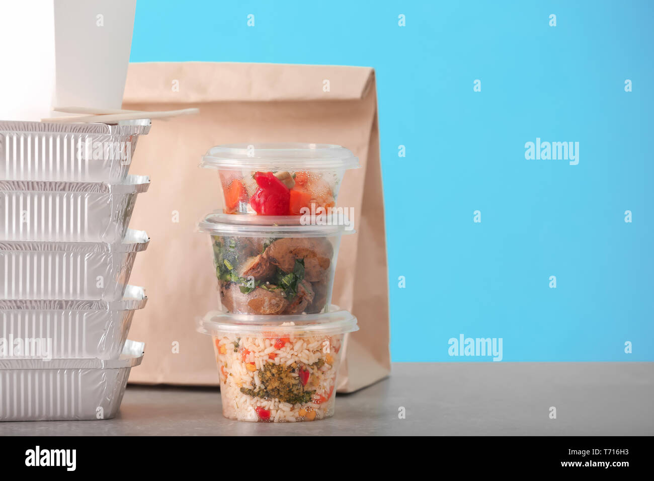 Different packages with delicious food on table against color ...